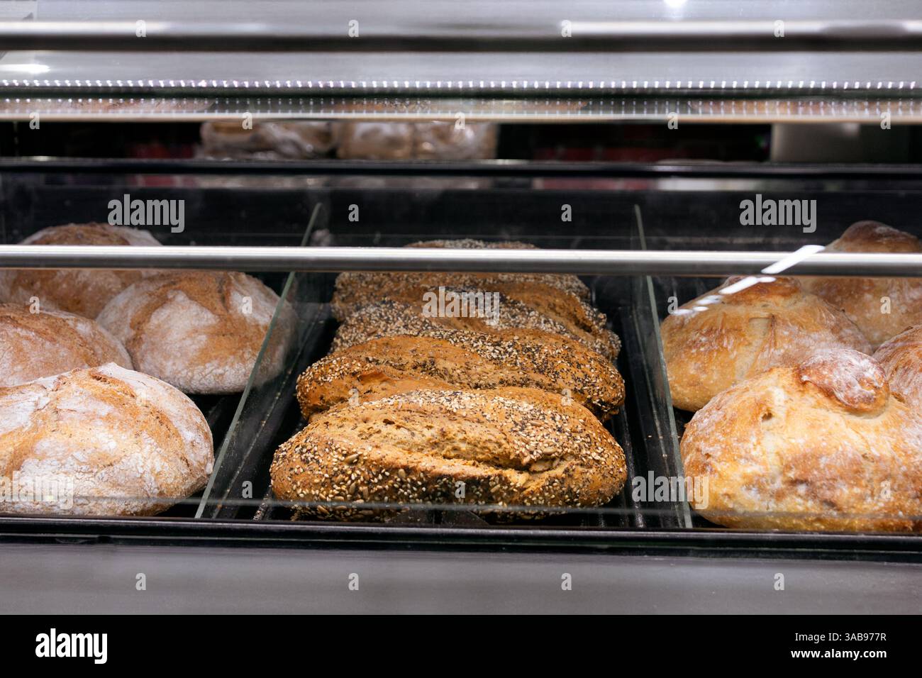 A selection of fresh artisanal bread showcased in a bakery display case ...
