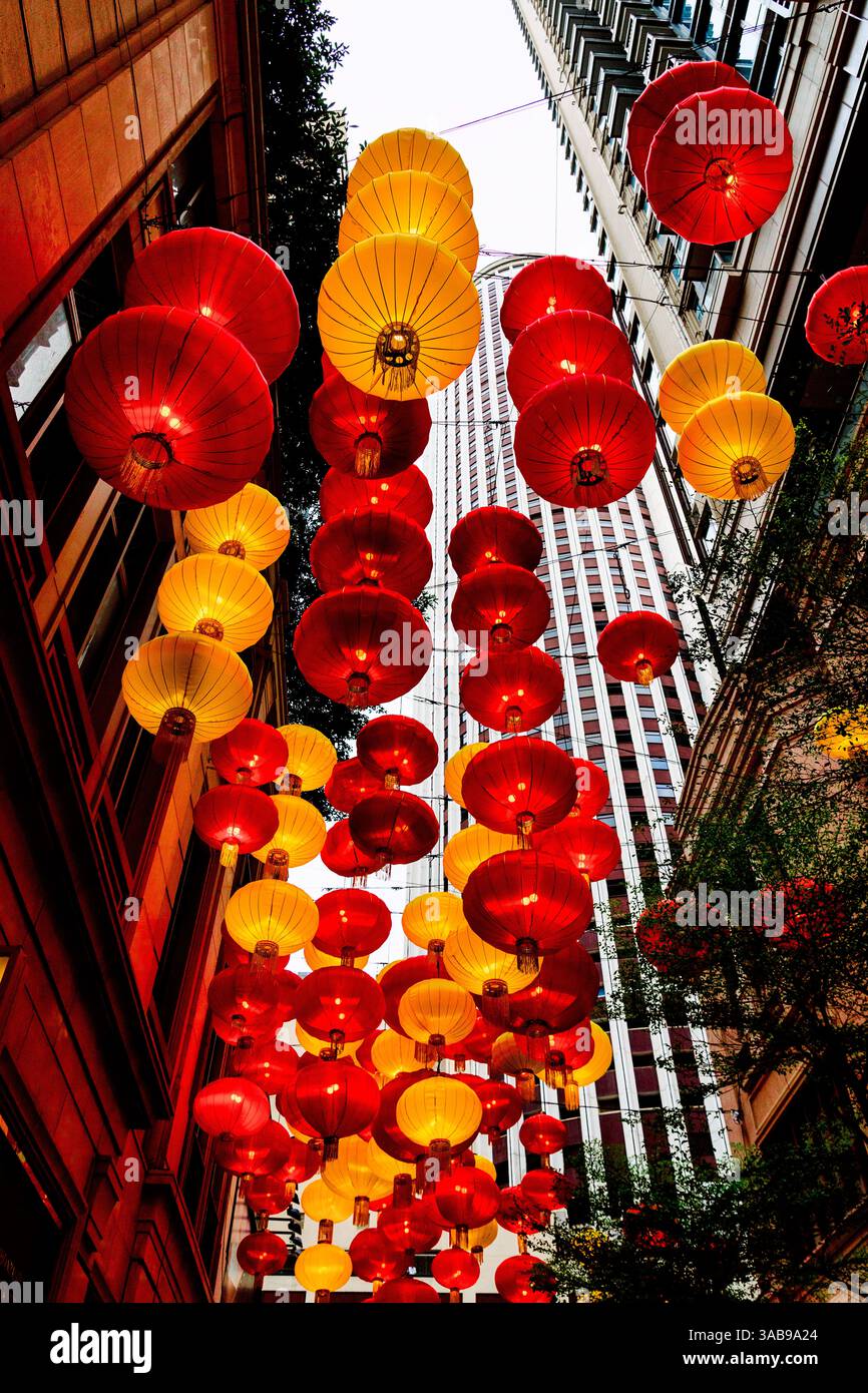 From below radiant red and yellow lanterns hang between skyscrapers in ...