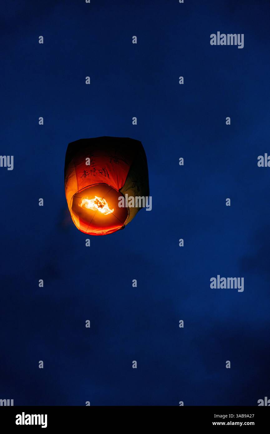 From below a vibrant Chinese floating lantern with handwritten wishes ...