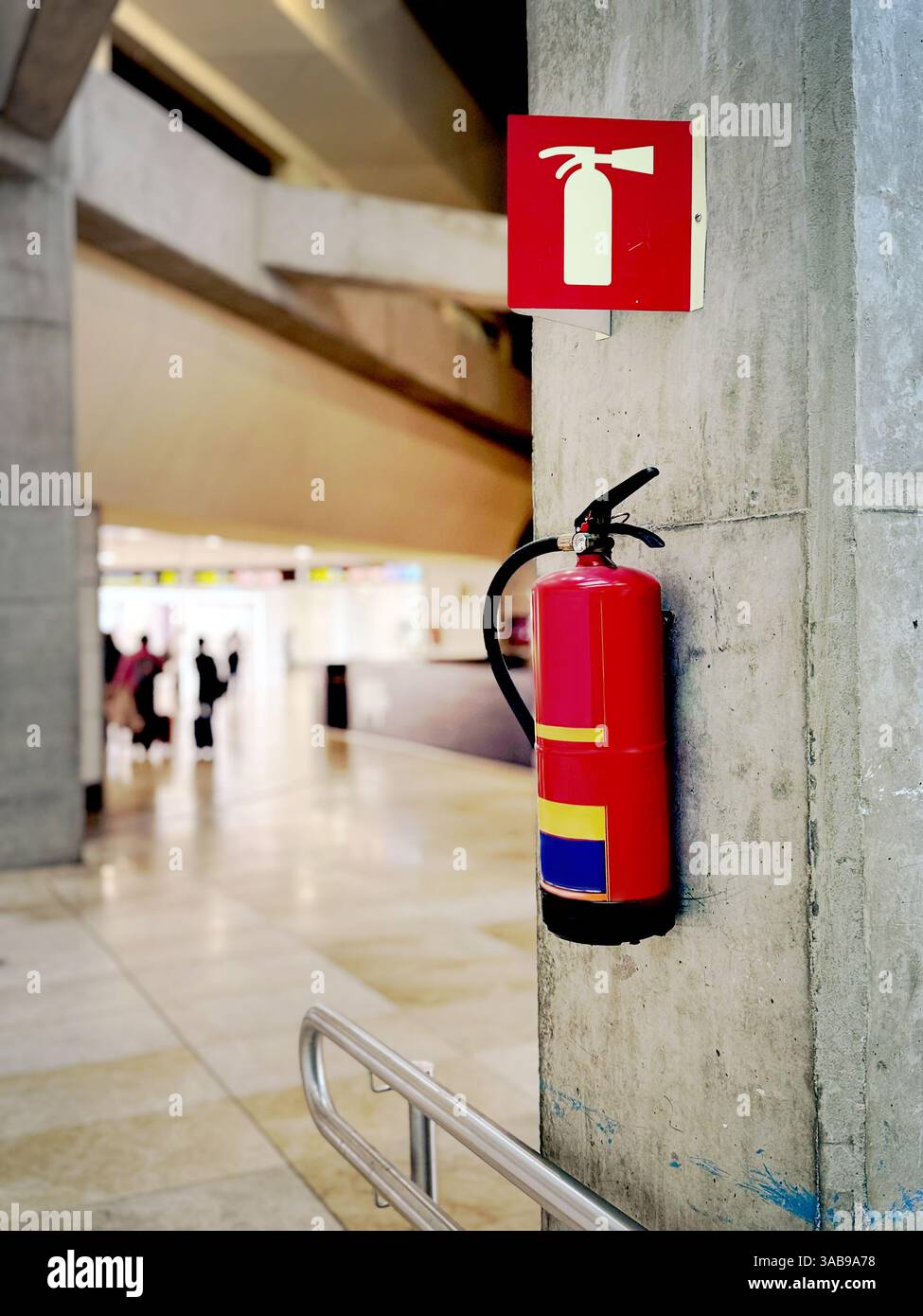 A red fire extinguisher mounted on a concrete wall in an airport ...