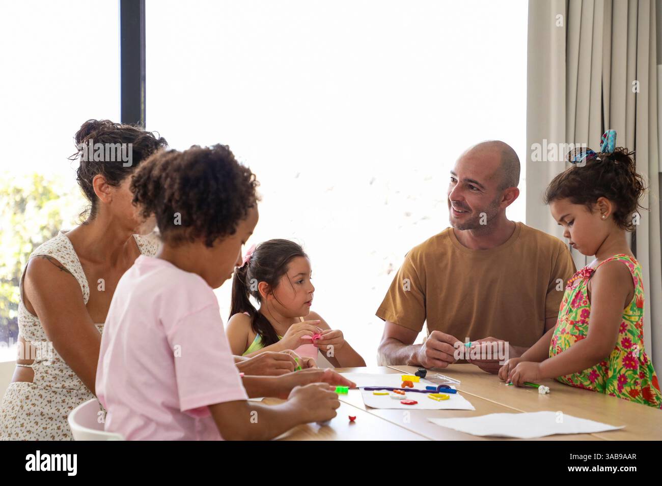 A family gathering around a table, engaging in creative activities with ...