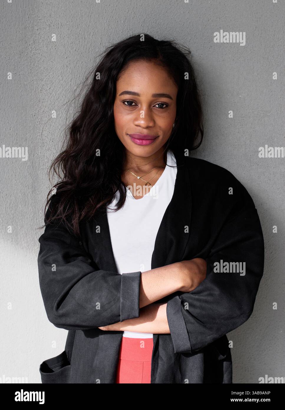 A confident black woman stands with arms folded, wearing a black jacket ...