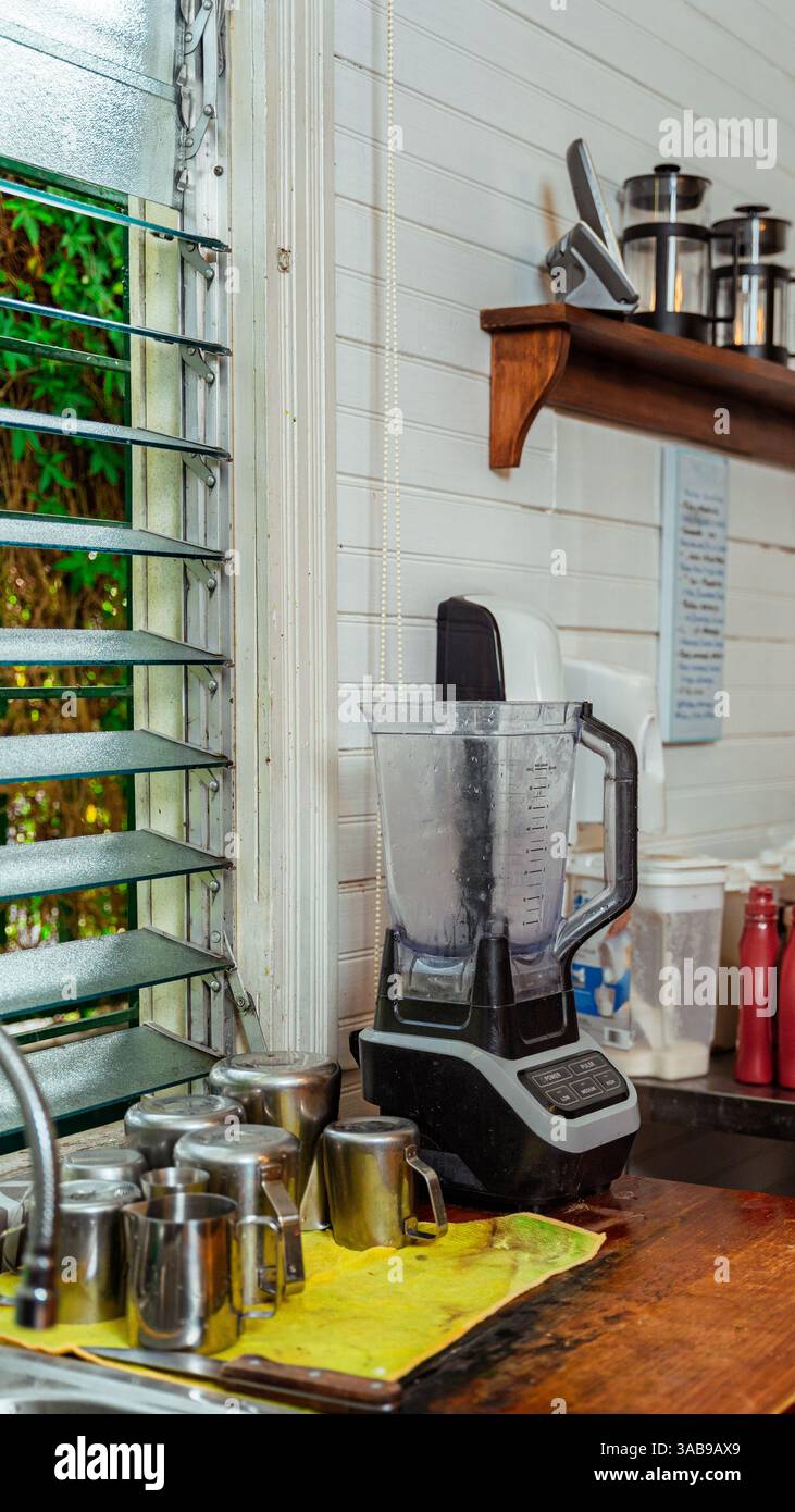 A cozy cafe scene featuring a blender alongside steel mugs on a wooden ...