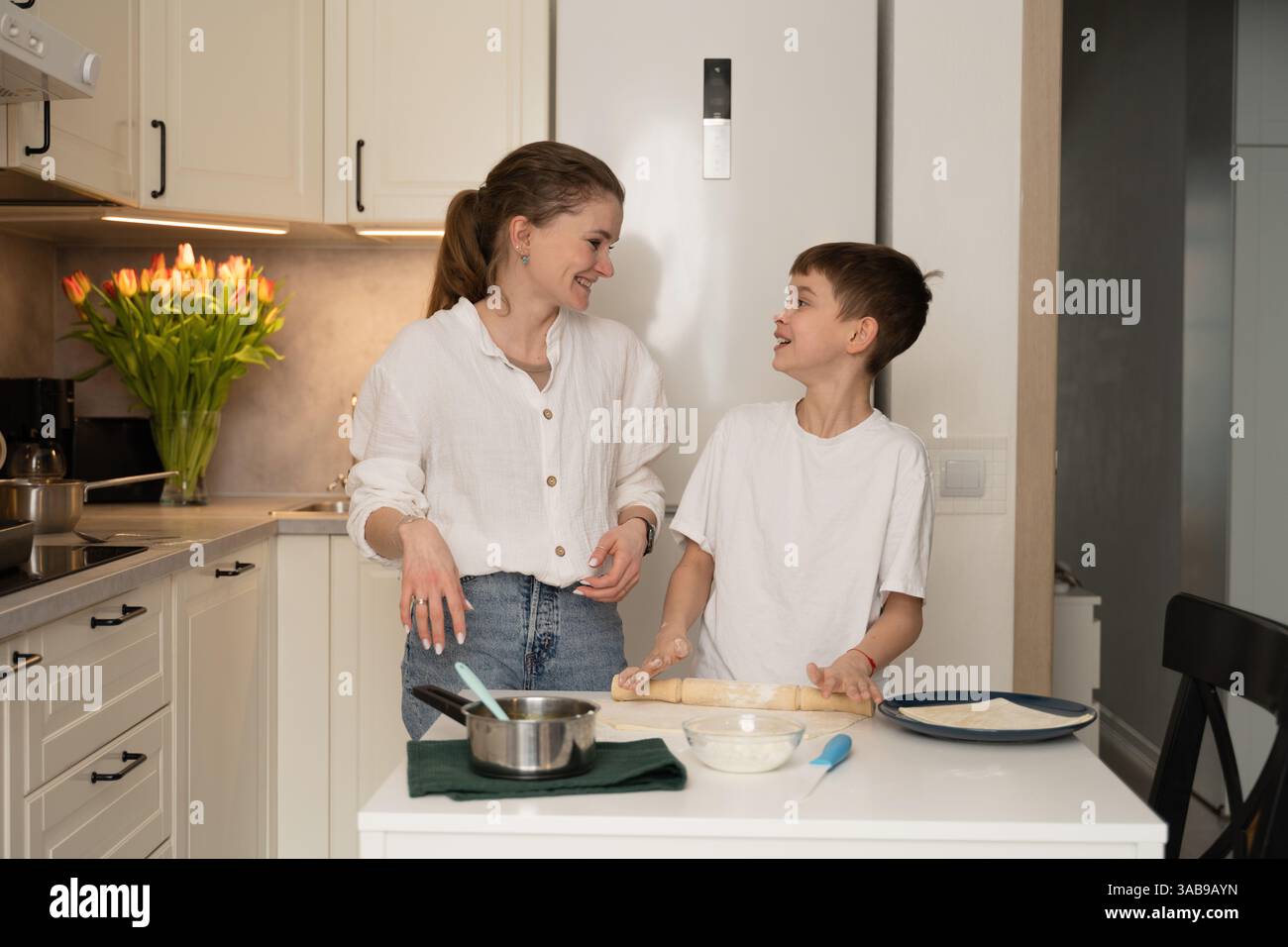 Mother and son engage in a joyful cooking session in a modern kitchen ...