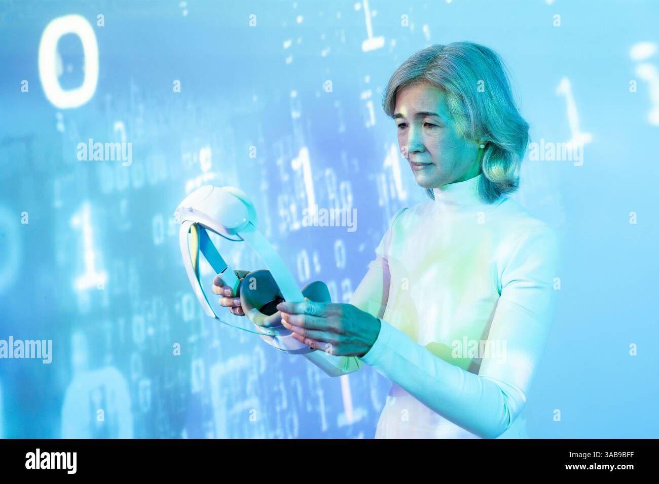 An elderly Asian woman engages with virtual reality technology, represented by a headset, set ...