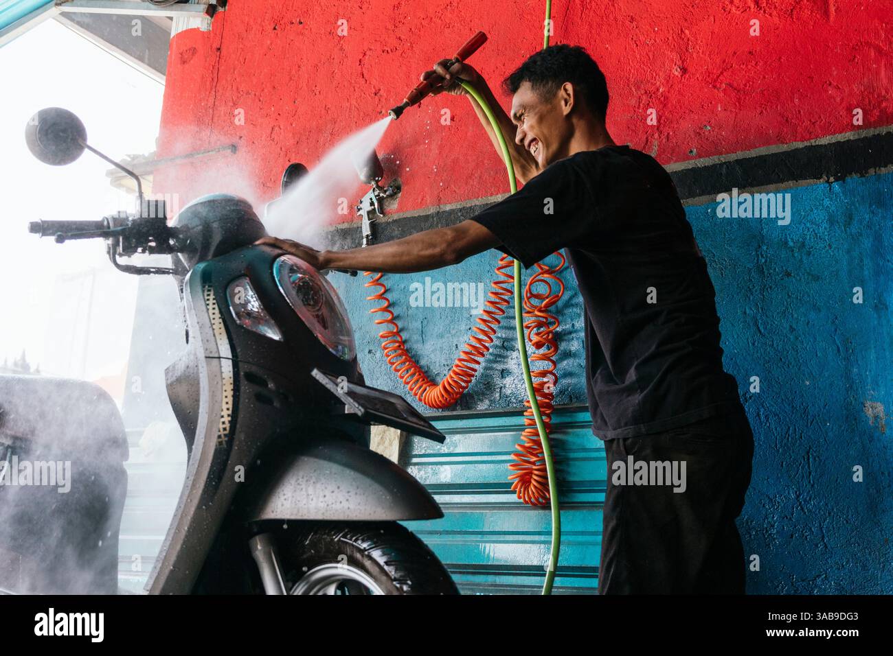 A professional motorcycle cleaner uses a pressure washer to thoroughly ...