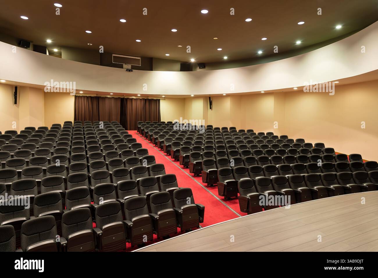 An empty convention center with rows of black seats and a vibrant red ...