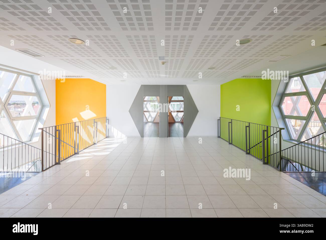 A modern auditorium hallway features hexagonal windows and vibrant ...