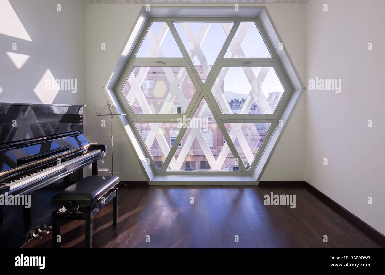 A modern auditorium room features a sleek black piano, a unique ...