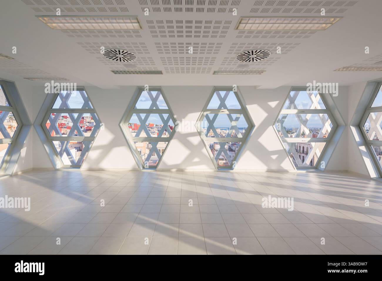 A modern auditorium room featuring hexagonal windows, white walls, and ...