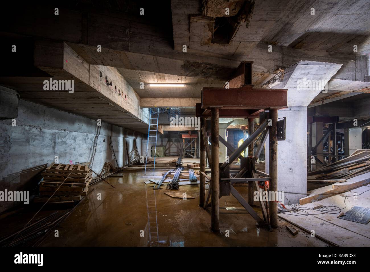 A dimly lit basement under construction, with structural beams and ...