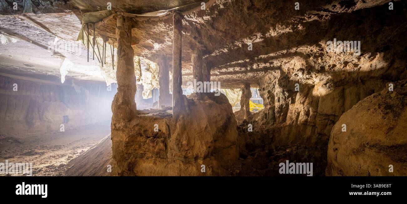 A deep underground excavation reveals exposed soil columns and eroded ...