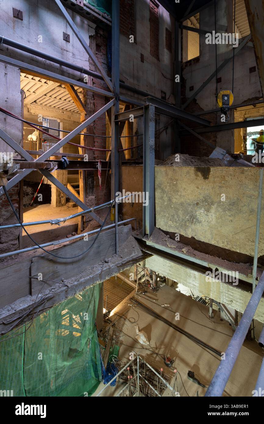 An indoor construction site with metal beams, scaffolding, and workers ...