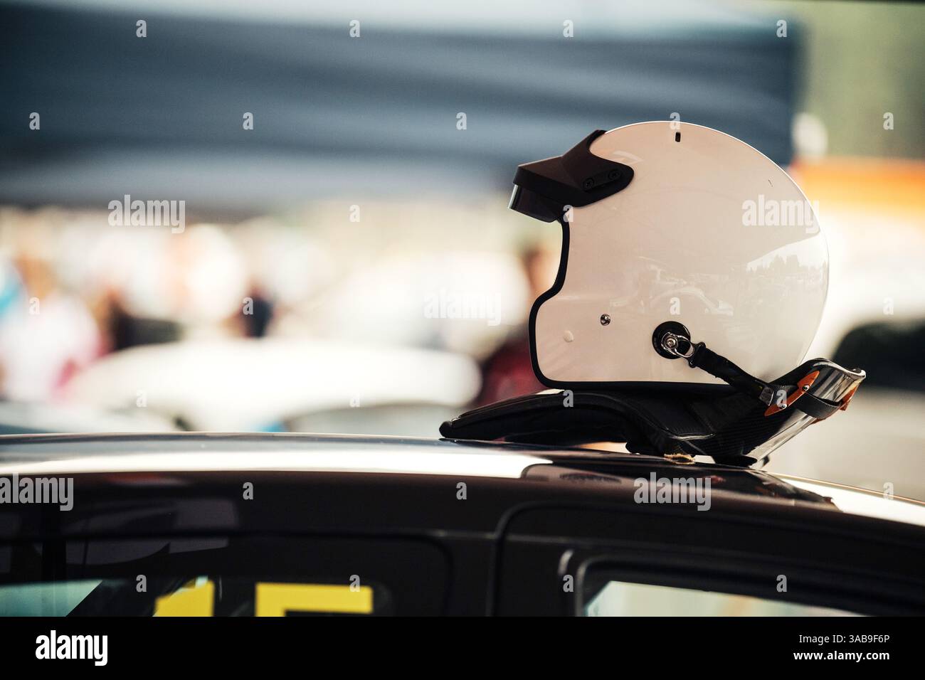 Close-up of a white racing helmet resting on a car's roof. Symbolizing ...