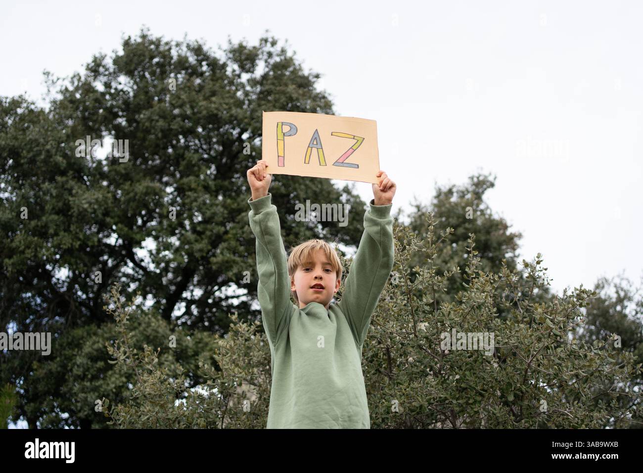 Child holding a paz sign, advocating for peace and harmony in a park ...