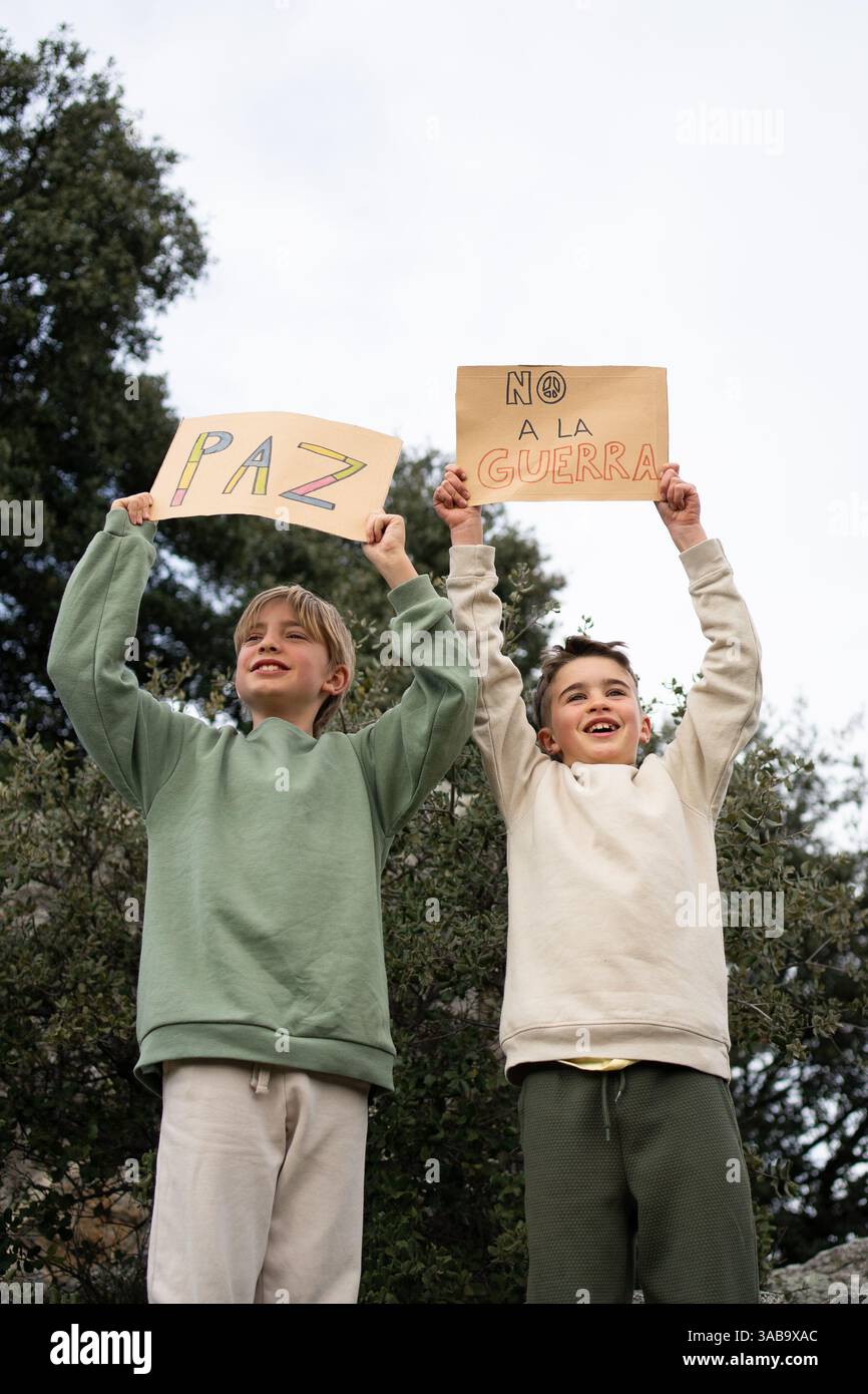 Two young boys holding signs with spanish words paz (peace) and no a la ...
