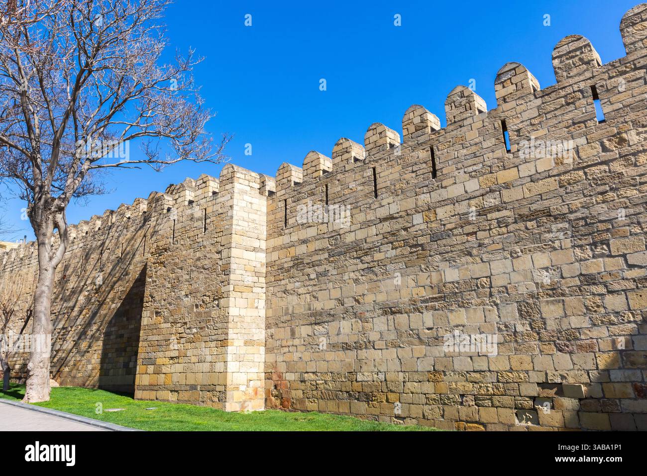 Ancient stone wall adorned with battlements, standing against a clear ...