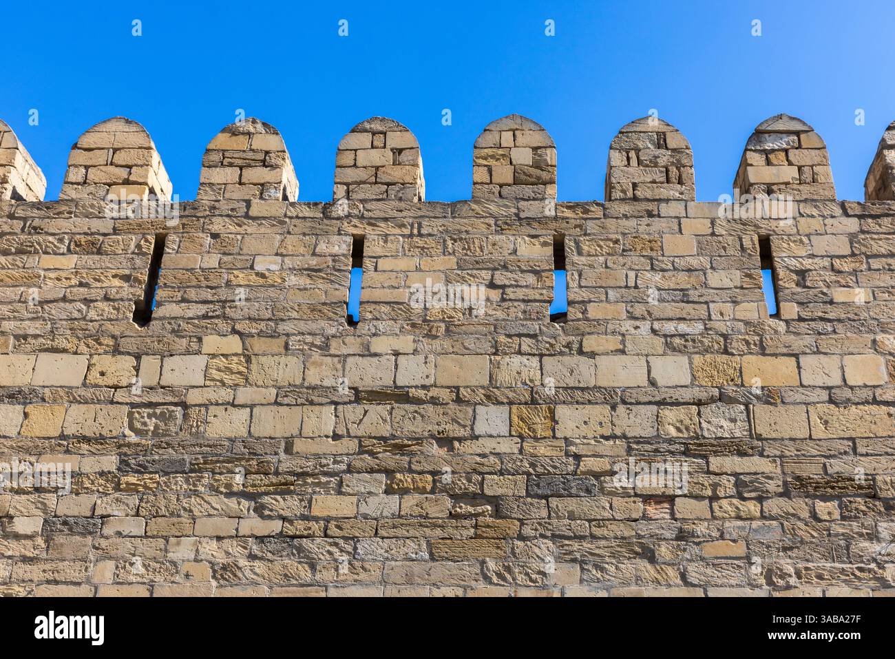Historic stone wall featuring crenellations and arrow slits, showcasing ...