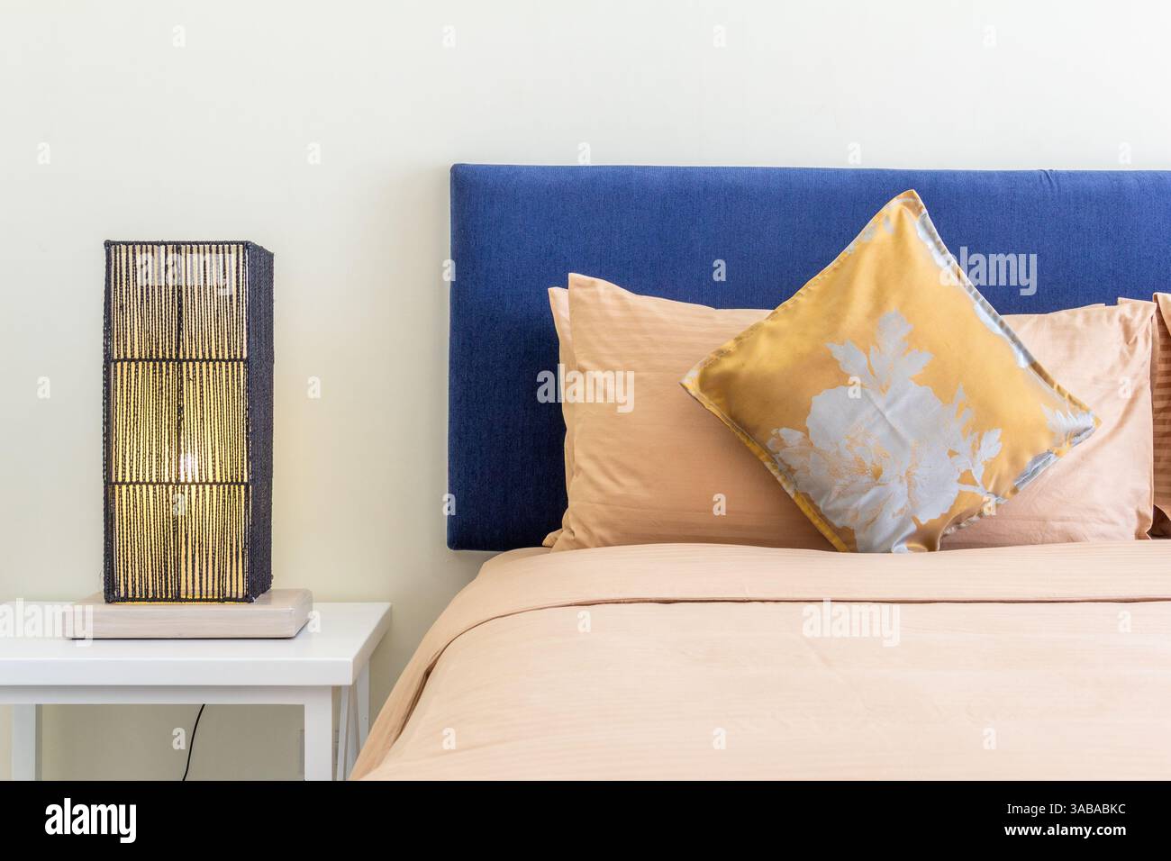 Comfy queen bed with plush pillows and blue headboard beside a modern ...