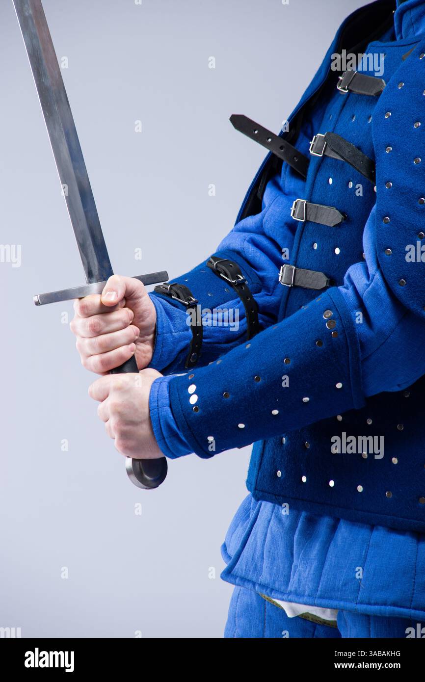 Hands Gripping Sword in Blue Armor. Close-up of medieval fighter ...