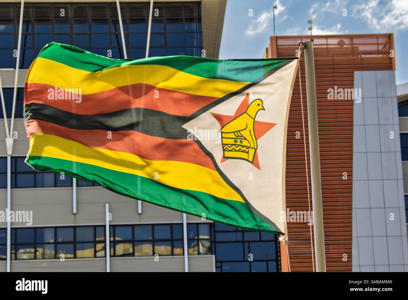 Zimbabwe country national flag on the pole, blue sky with clouds Stock ...