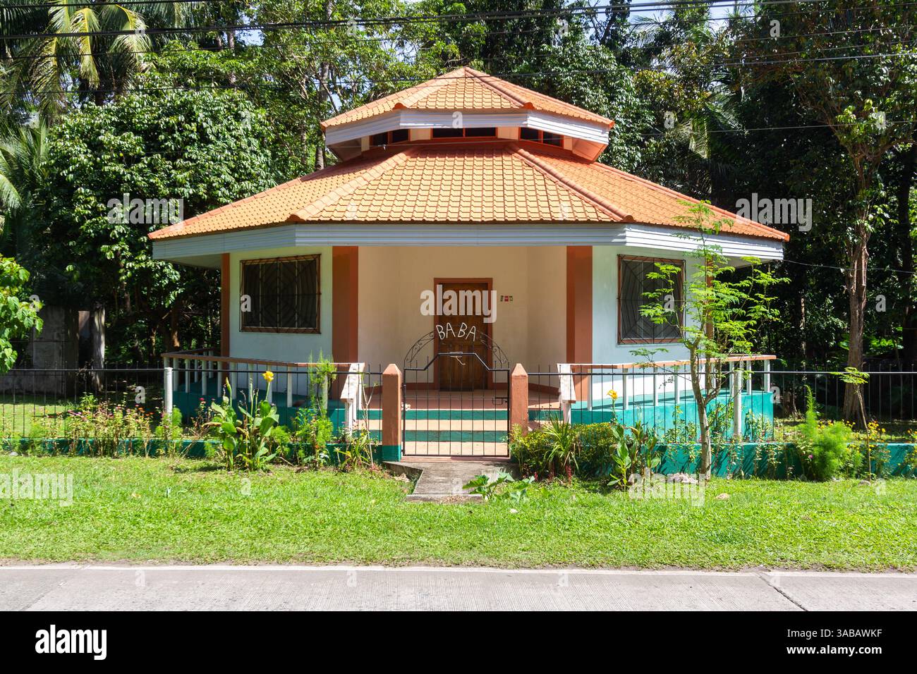 A small octagonal house with a unique design standing by the roadside ...