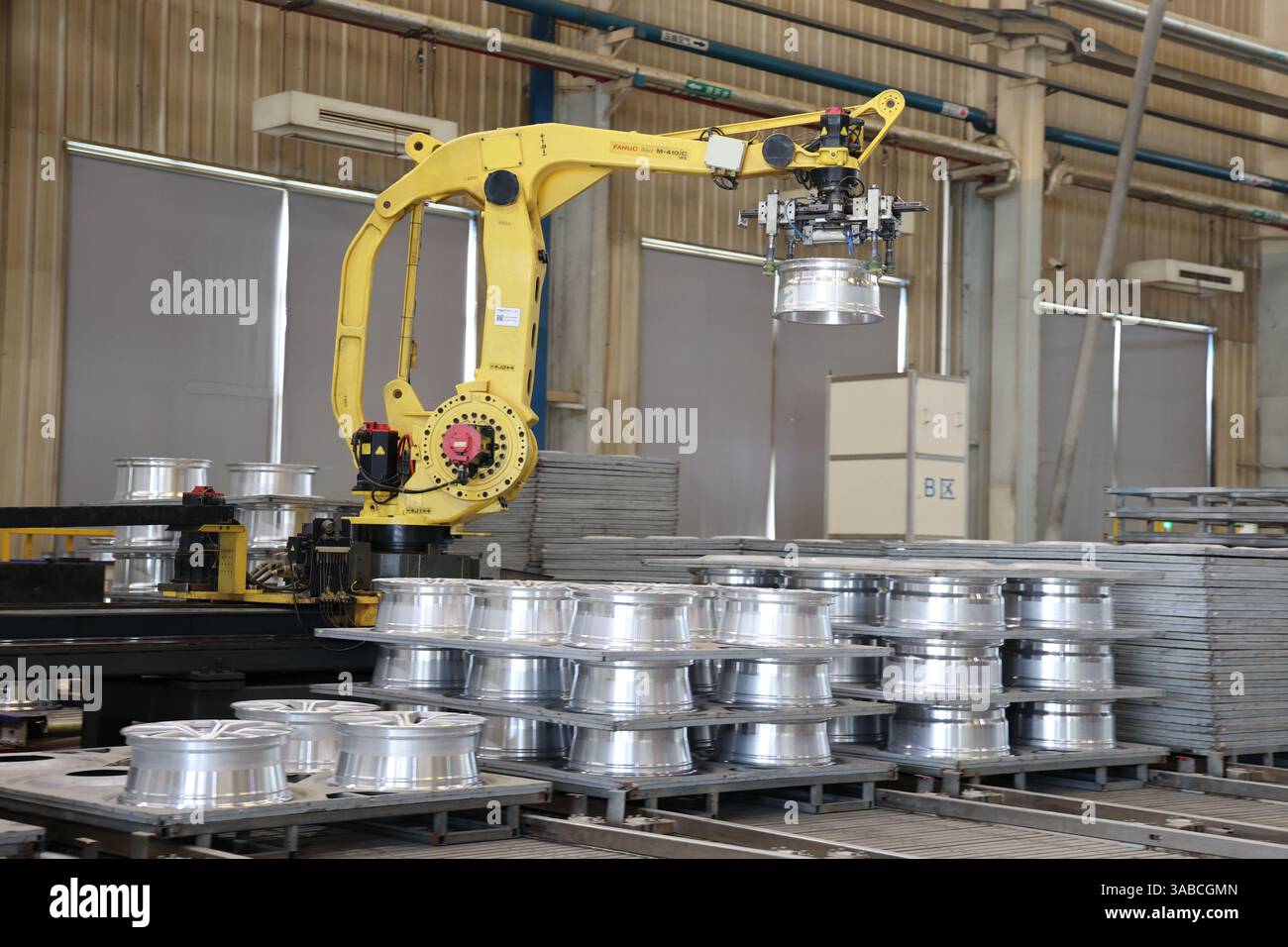 An industrial robot produces wheel hub products at an automobile wheel ...