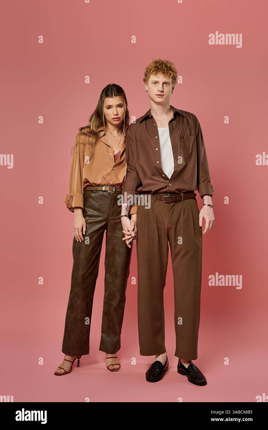 A young couple displays stylish outfits, holding hands with romance and ...