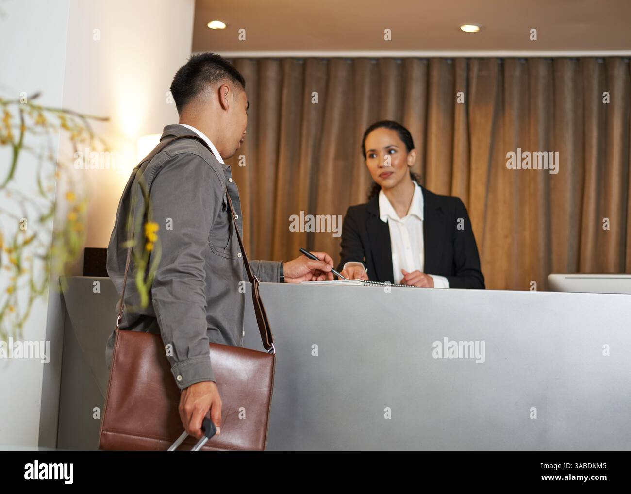 Traveller Checking In at a Hotel Reception Desk with Friendly Staff ...