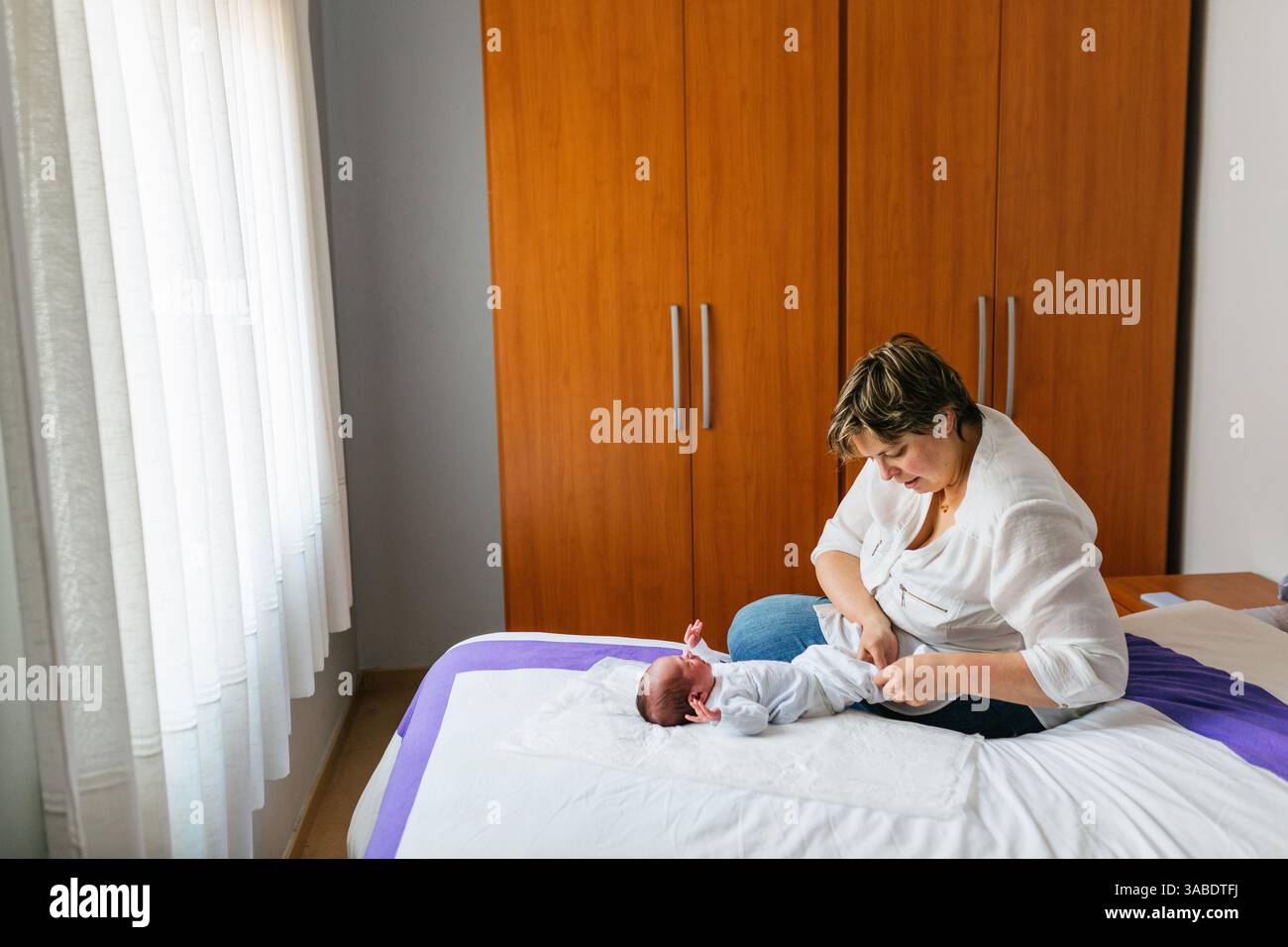 Mother changing diaper of one month old baby son on bed Stock Photo - Alamy