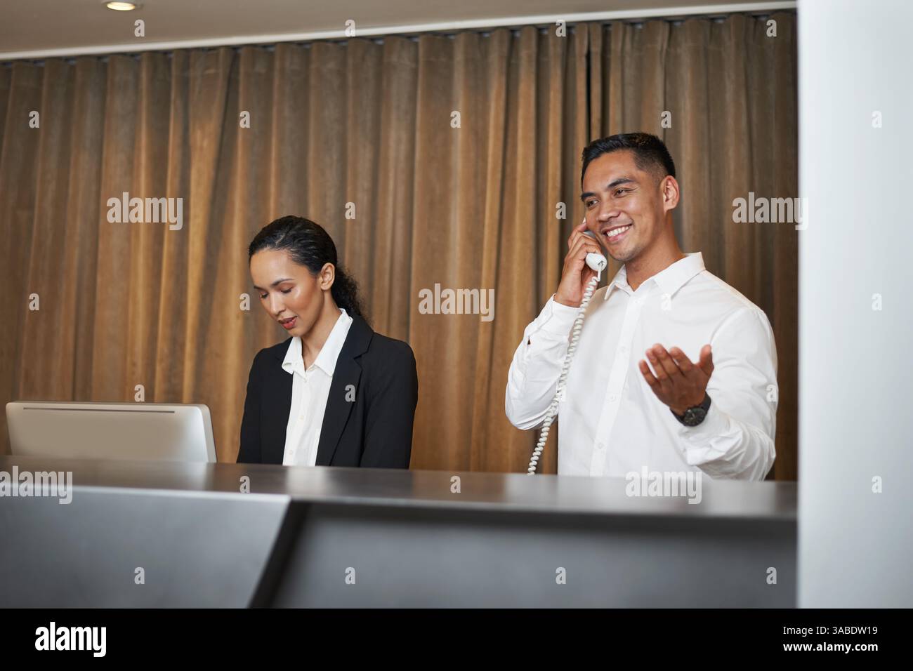 Hotel Receptionists Engaged in Work Tasks at a Modern Hotel Front Desk ...