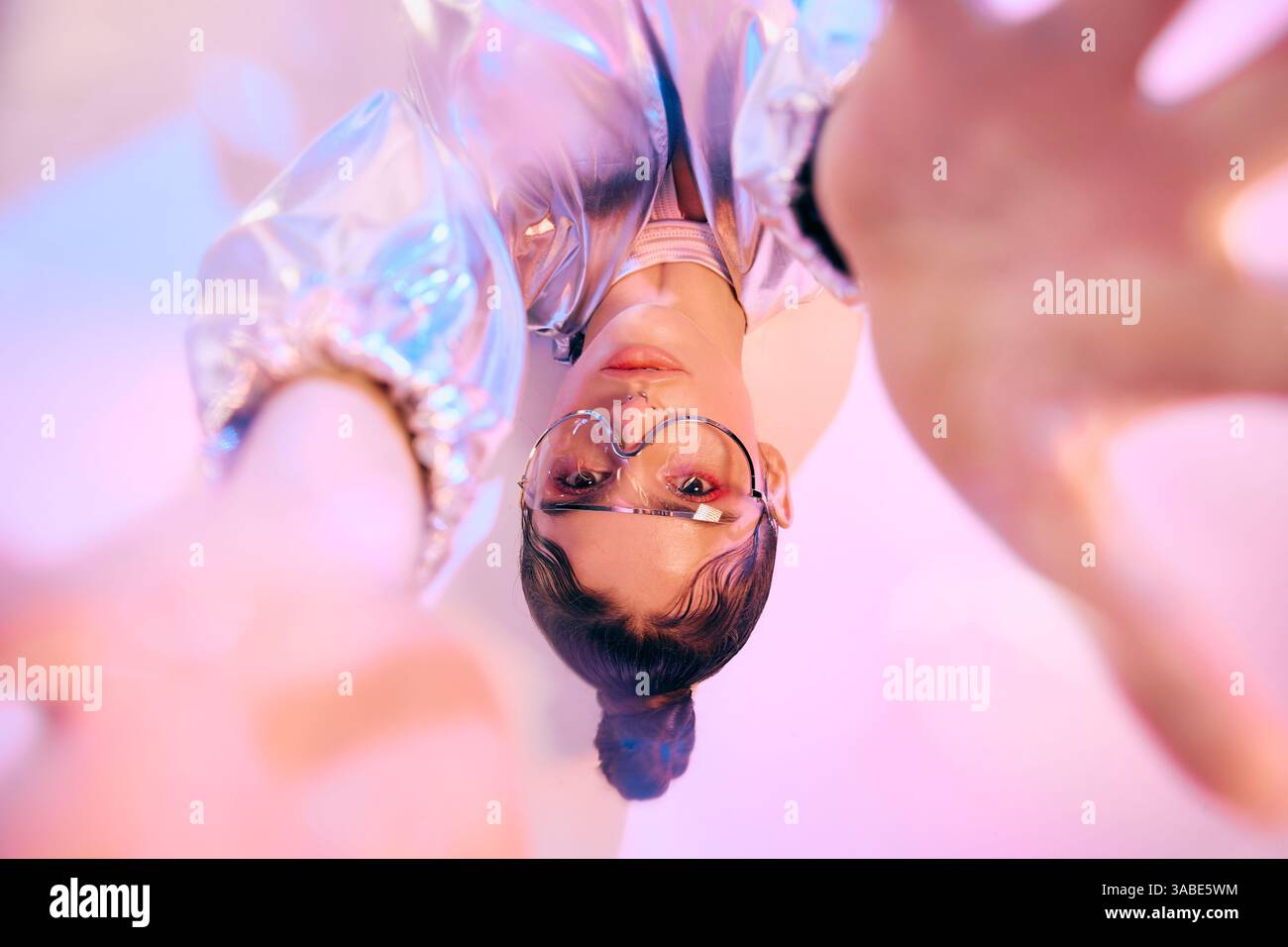 A young woman models her modern holographic outfit in a colorful ...