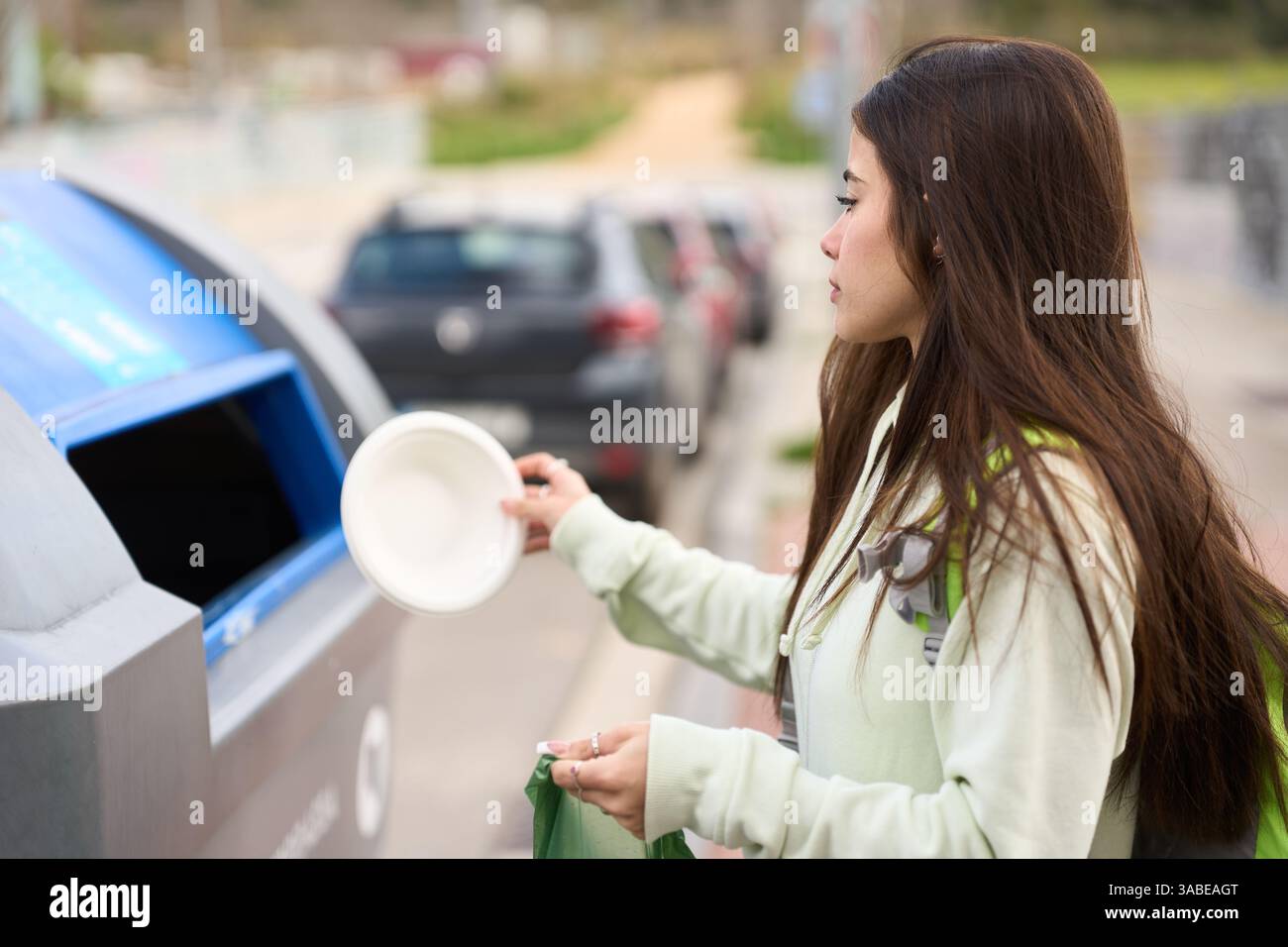 Young woman throwing a paper plate in the recycling bin Stock Photo - Alamy
