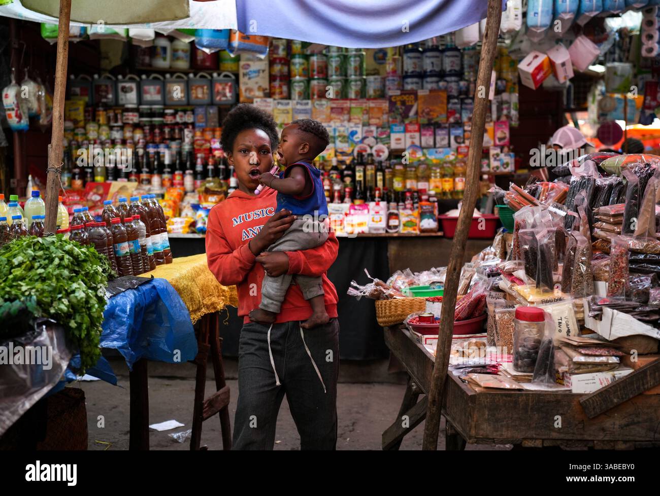 Antananarivo, Madagascar. 28th Mar, 2025. A vendor soothes a child at the Analakely market in ...