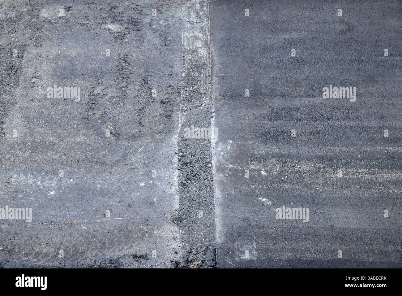 Close-up of a road resurfacing process showing the contrast between old ...
