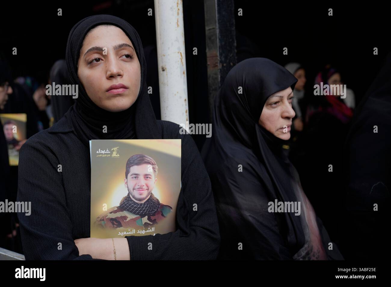 A woman holds a portrait of a Hezbollah fighter Ali Bdeir, the son of a ...