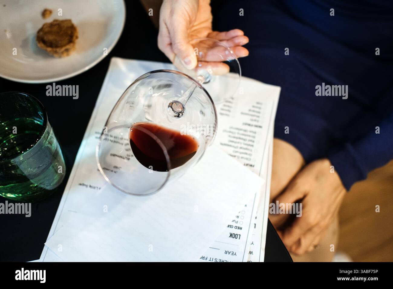 Wine glass tilted over tasting notes at a fine dining table. Curated ...