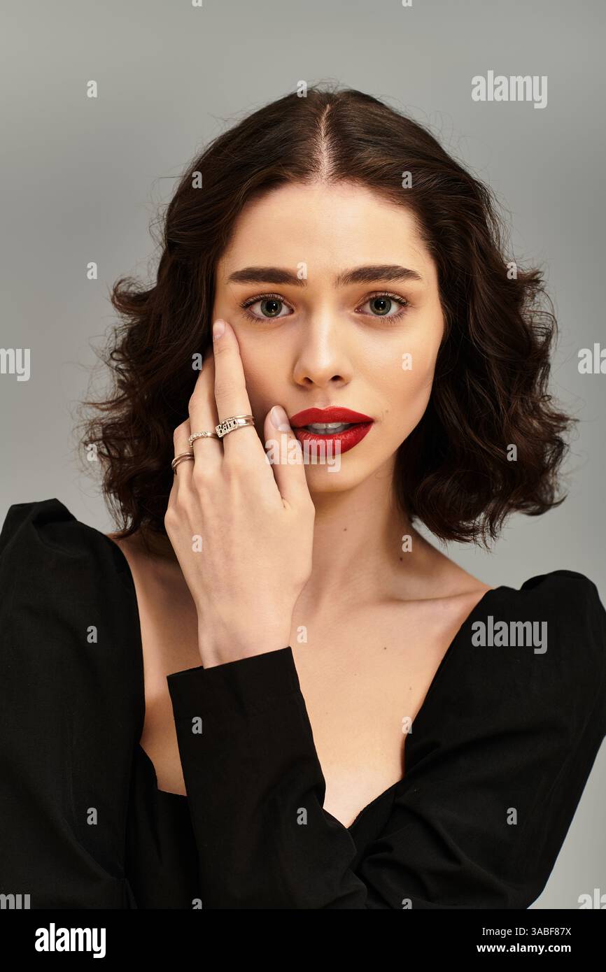A young woman poses gracefully, highlighting her red lips and natural ...