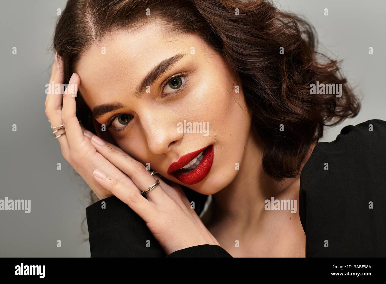 Young woman with braces poses elegantly against a grey backdrop ...