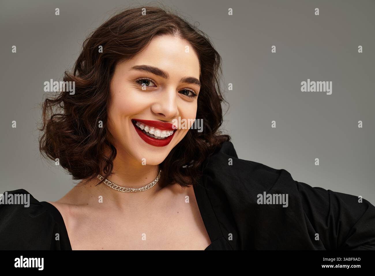 A joyful young woman showcases her radiant smile, adorned with braces ...