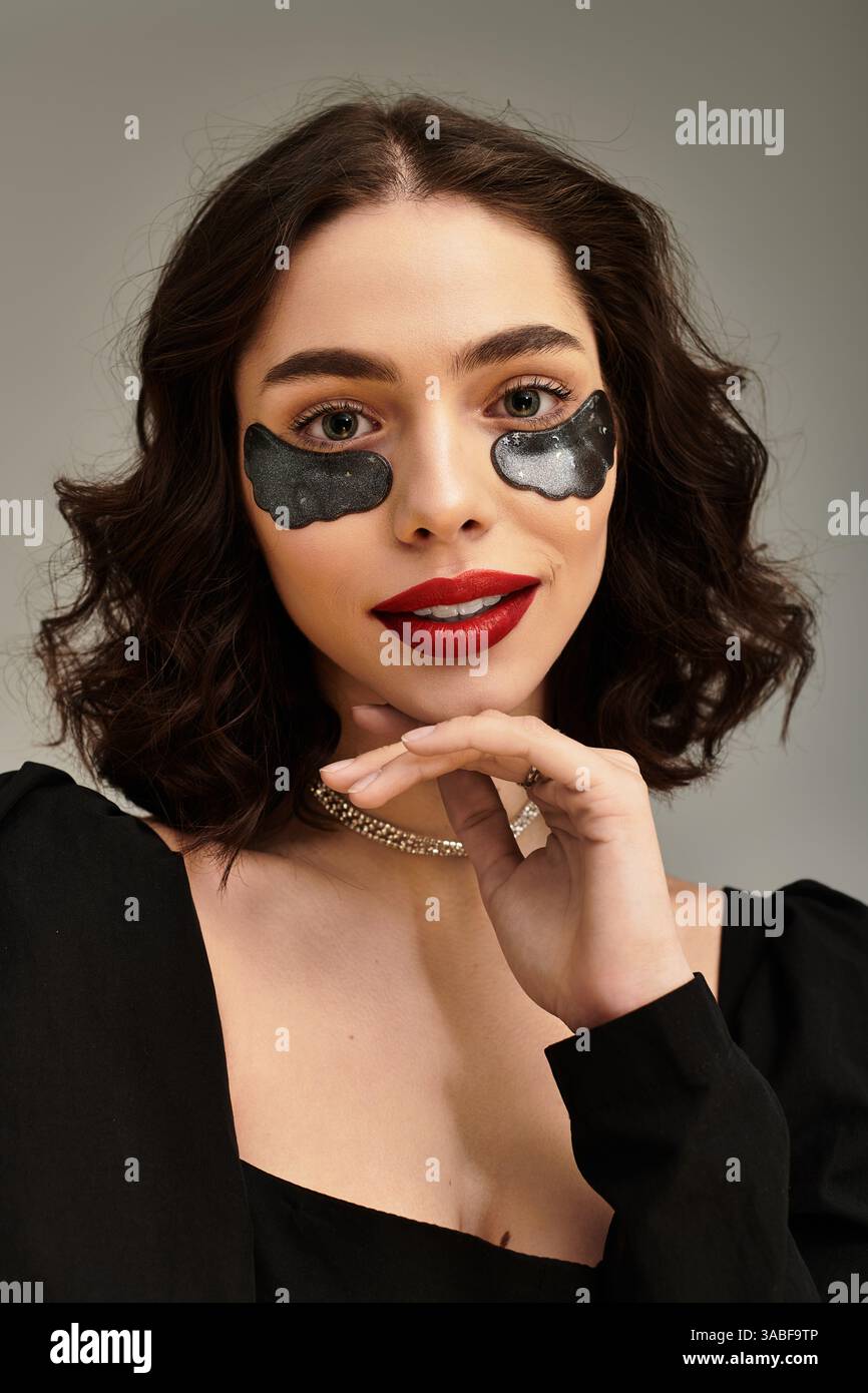 A beautiful young woman with glossy red lips poses gracefully with ...