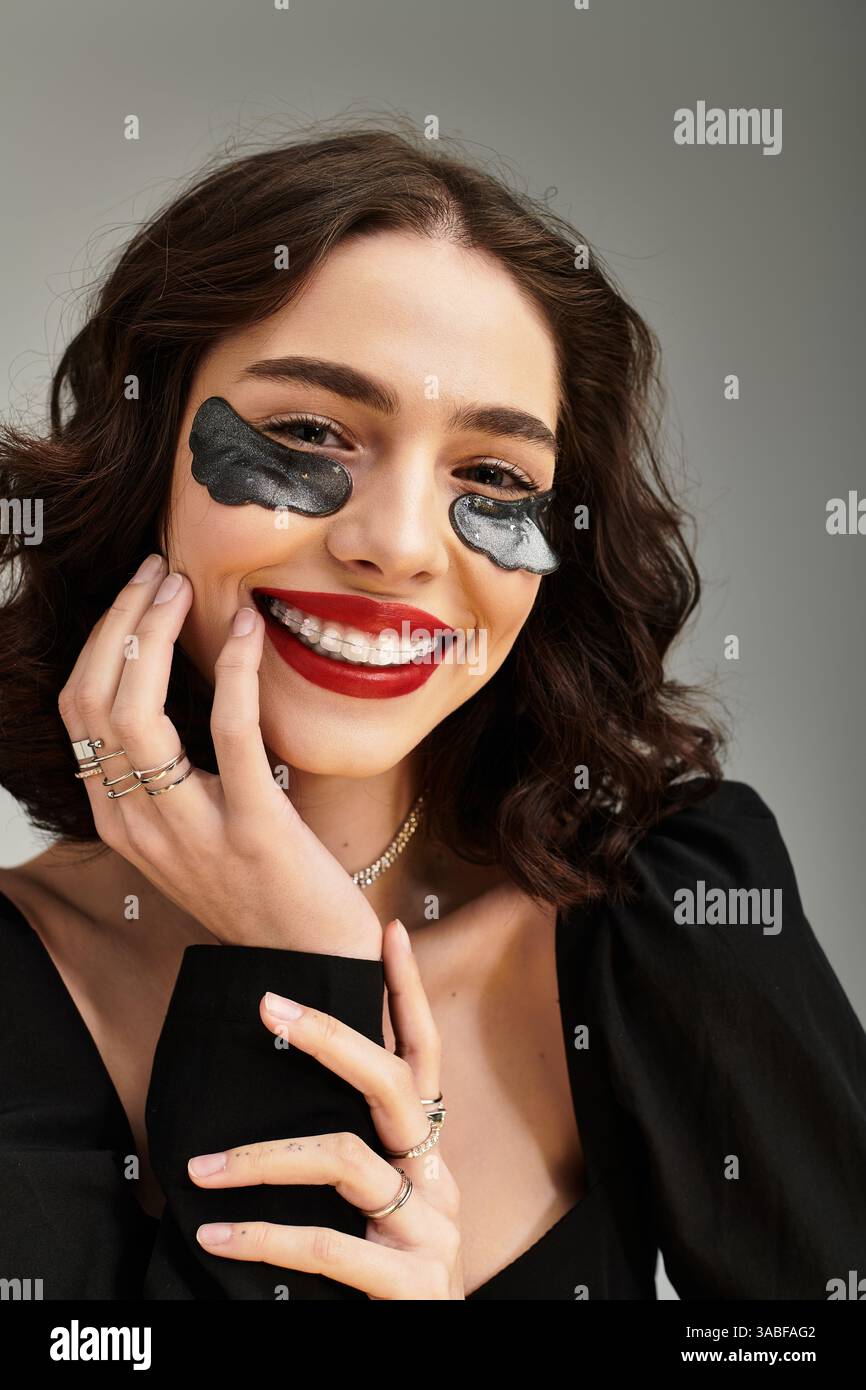 Bright smile lights up the grey backdrop as the young woman poses ...
