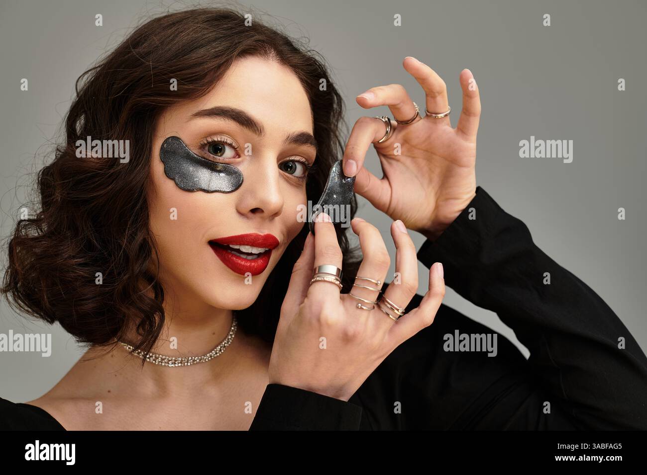 A charming young woman with braces poses playfully while applying under ...