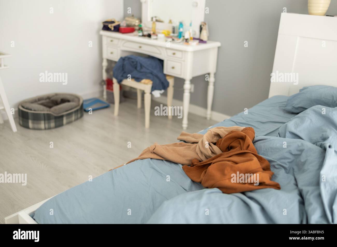 Unmade bed with scattered clothes in cozy bedroom scene. Domestic mess ...