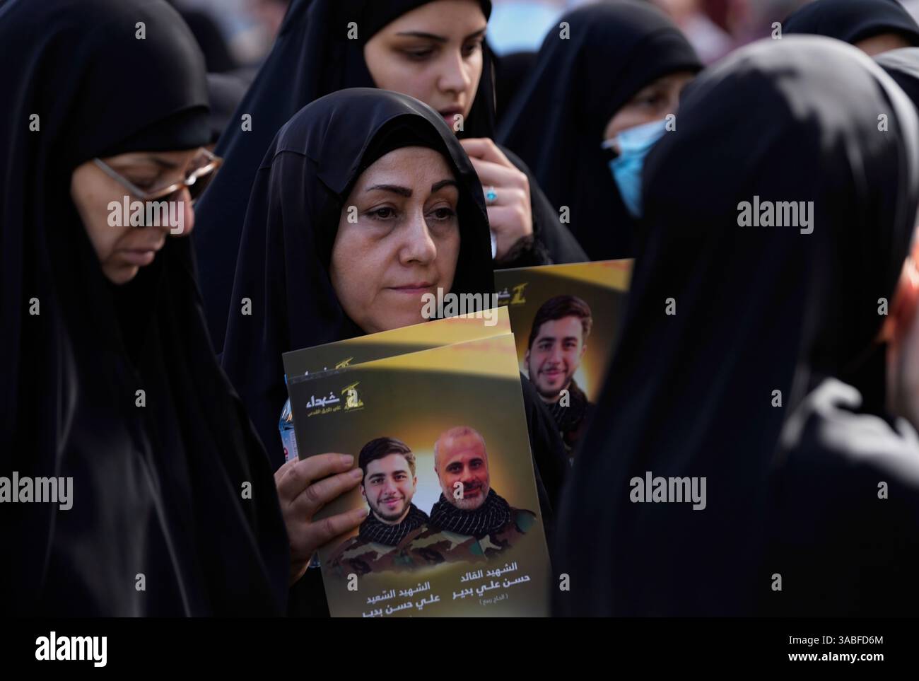 A mourner holds images of Hezbollah official Hassan Bdeir and his son ...