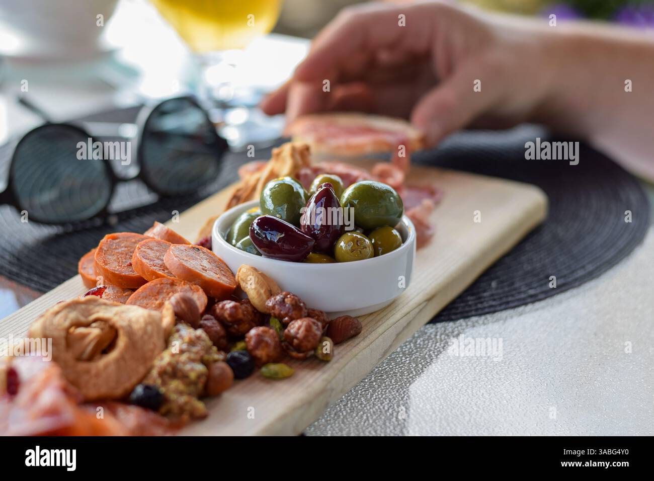 Man's hand taking food from charcuterie board with cured meats and ...