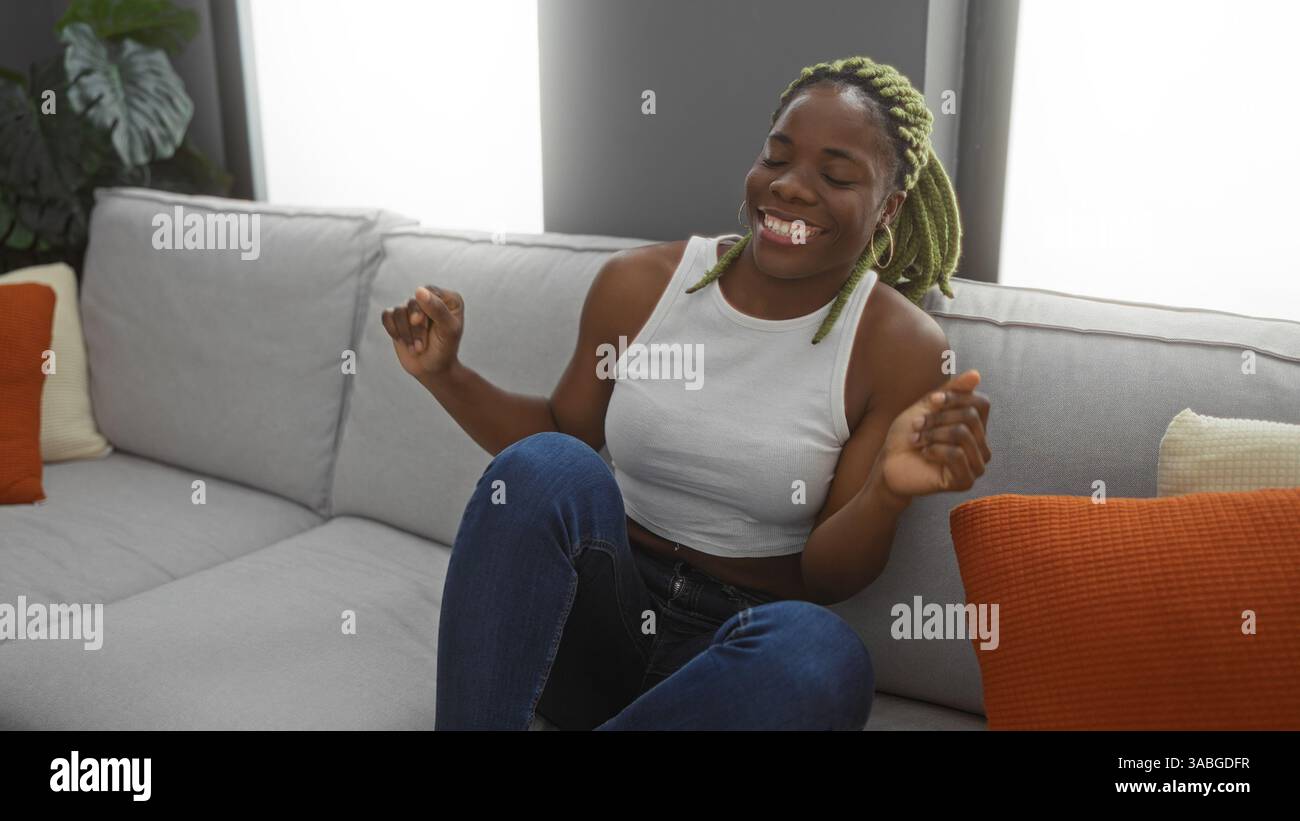 Woman dancing joyfully on a cozy sofa in a bright living room ...