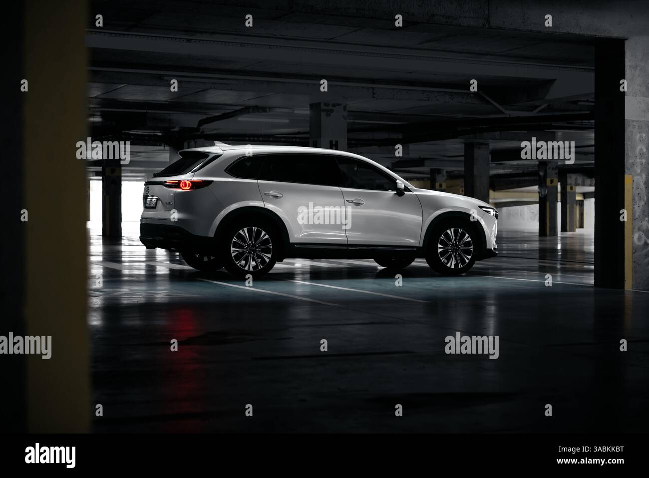 White Mazda CX-9 in parking garage under light well. Side view of ...