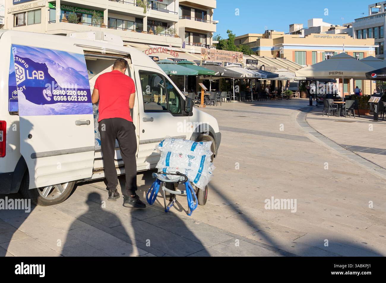 Crete.Greece - april 02, 2025: Ice delivery worker unloading bags from ...