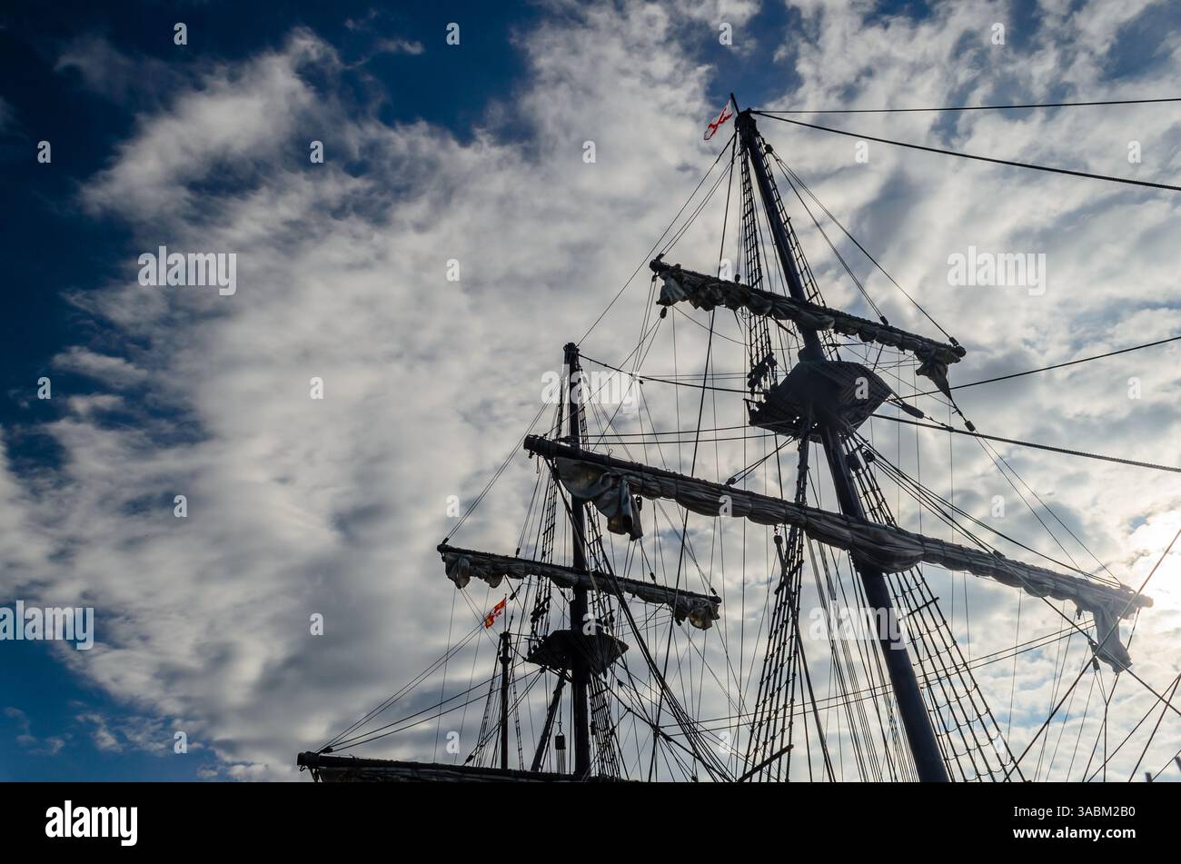 Upward view of tall ship rigging reaching up to a circular cloud above ...